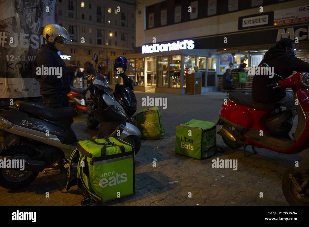 A fast food delivery man checks his phone while waiting for orders on ...