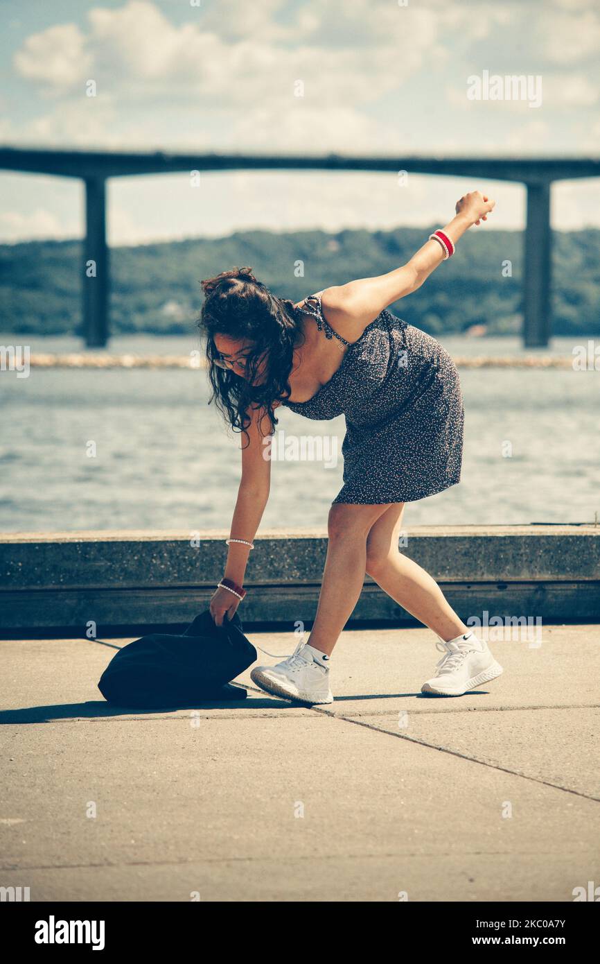 A vertical shot of a South Asian girl in a dress, picking up a jacket ...