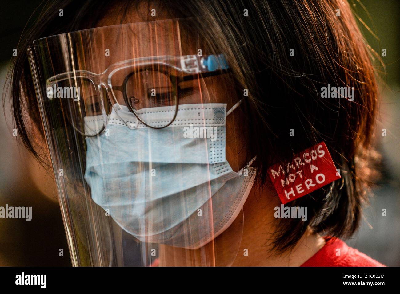 A woman wearing a face mask, a face shield, and an earring with the ...