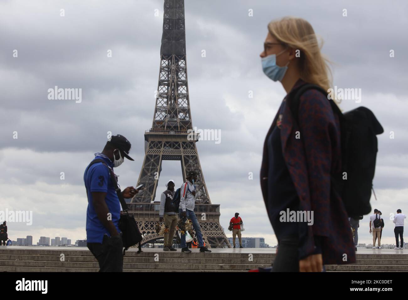 People wearing face masks walk on the Trocadero esplanade, a front the ...