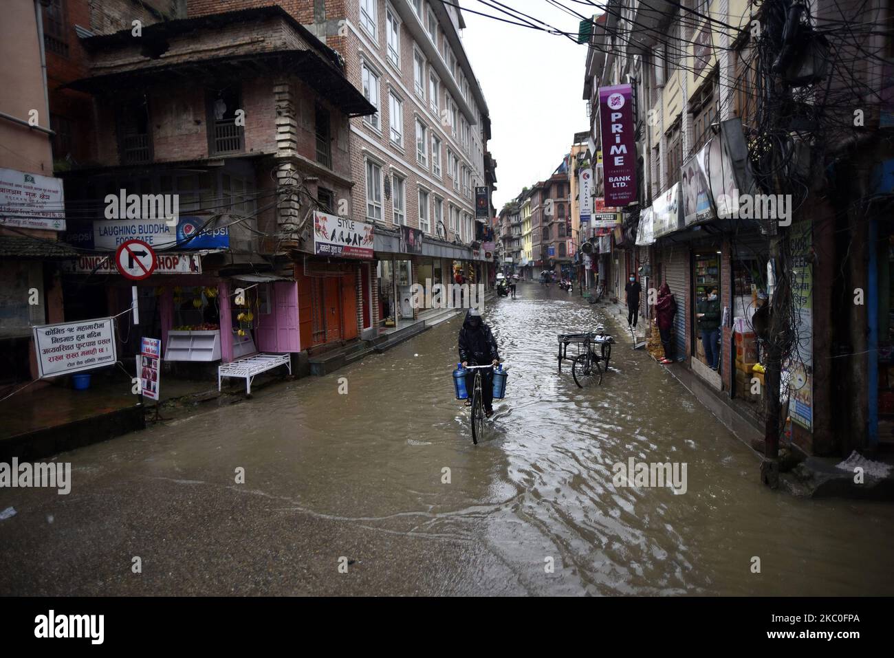 A cycle carrying drinking water jars through a water logged road at ...