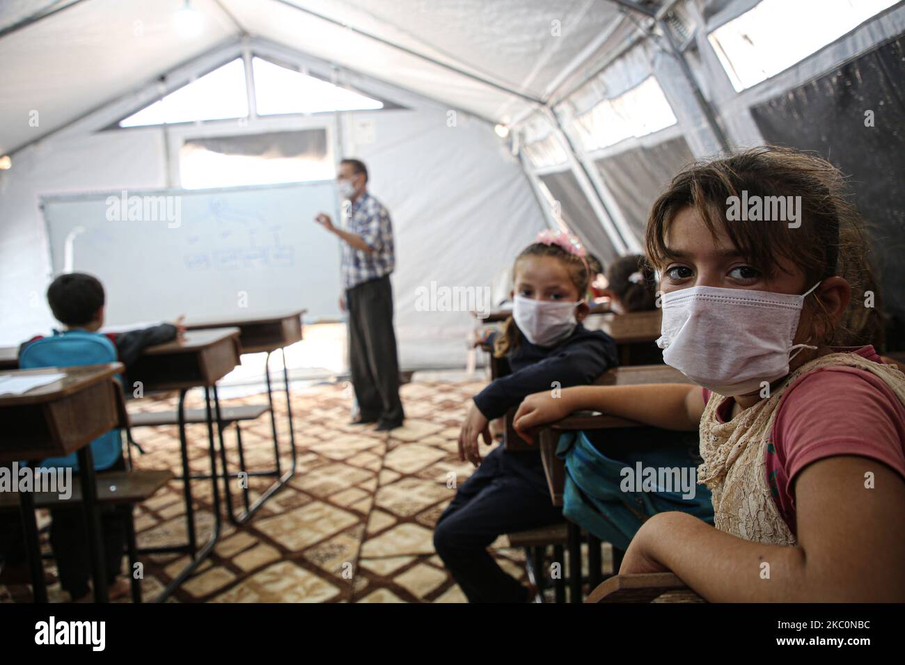 Syrian students wearing protective masks sit on their seats during the ...