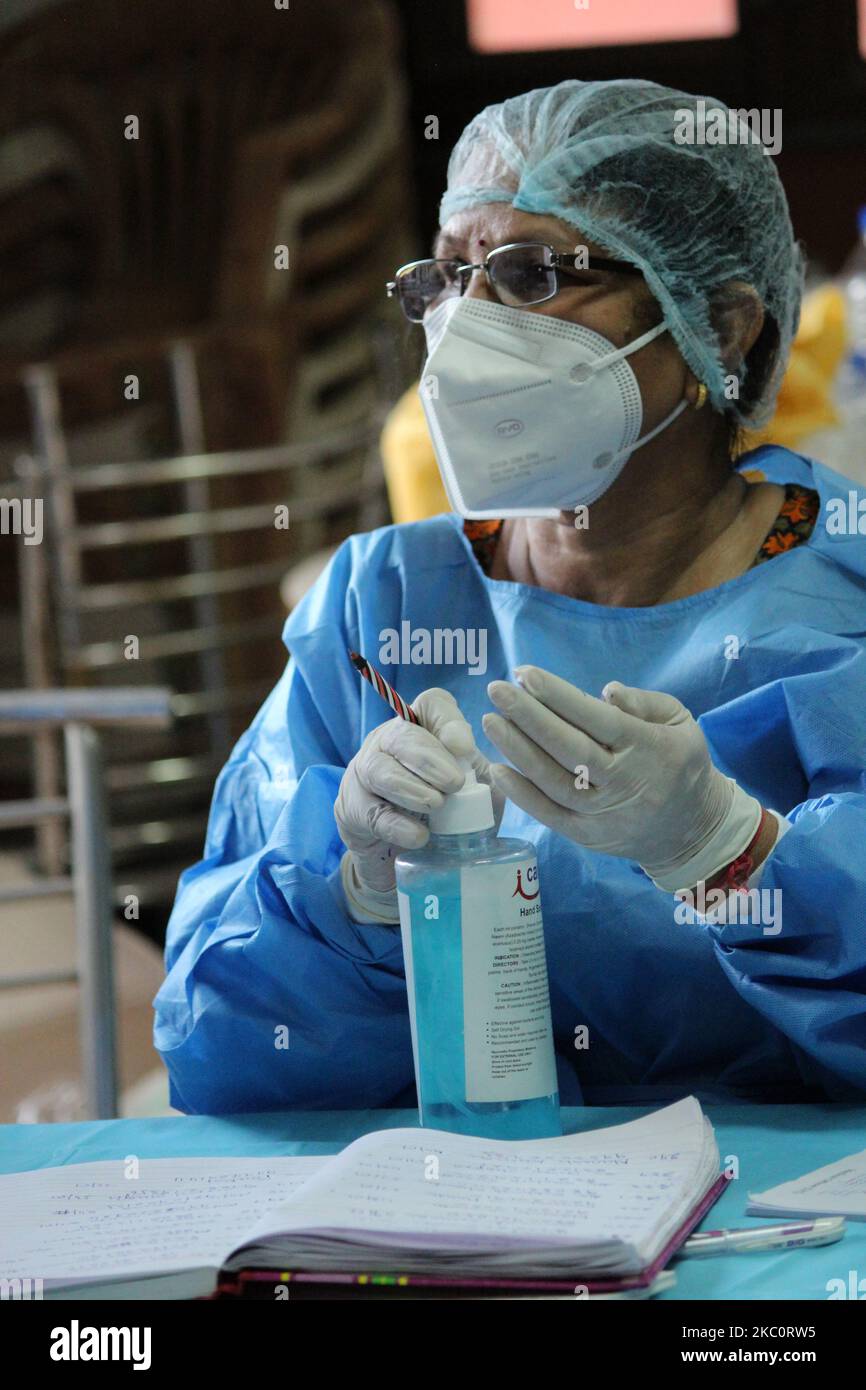 A health worker in personal protective equipment (PPE) registers staff ...