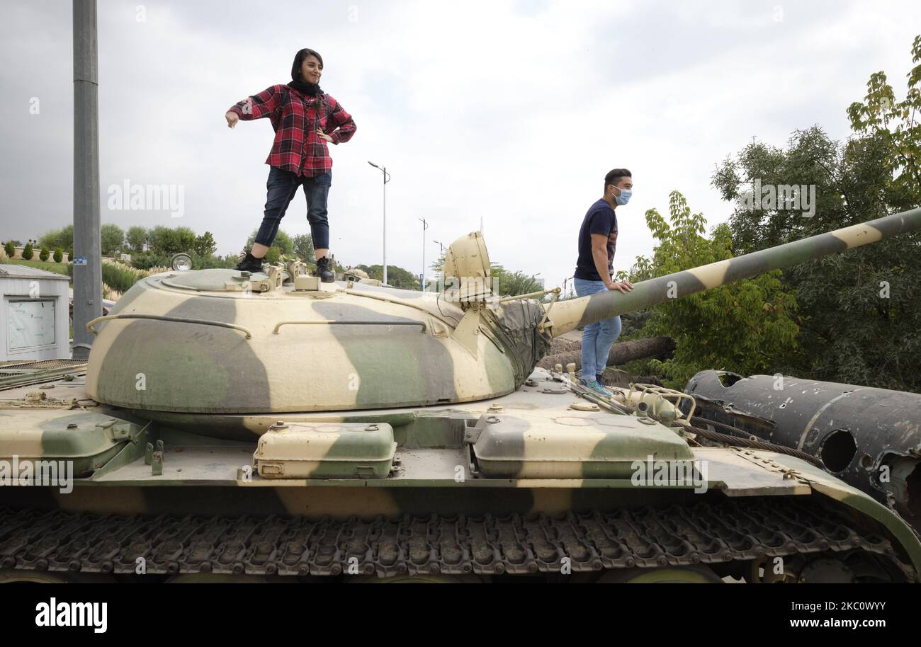 An Iranian man and a woman stand on a military tank while visiting of ...