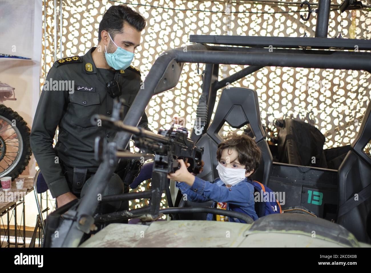 An Iranian policeman wearing a protective face mask looks on his son as ...