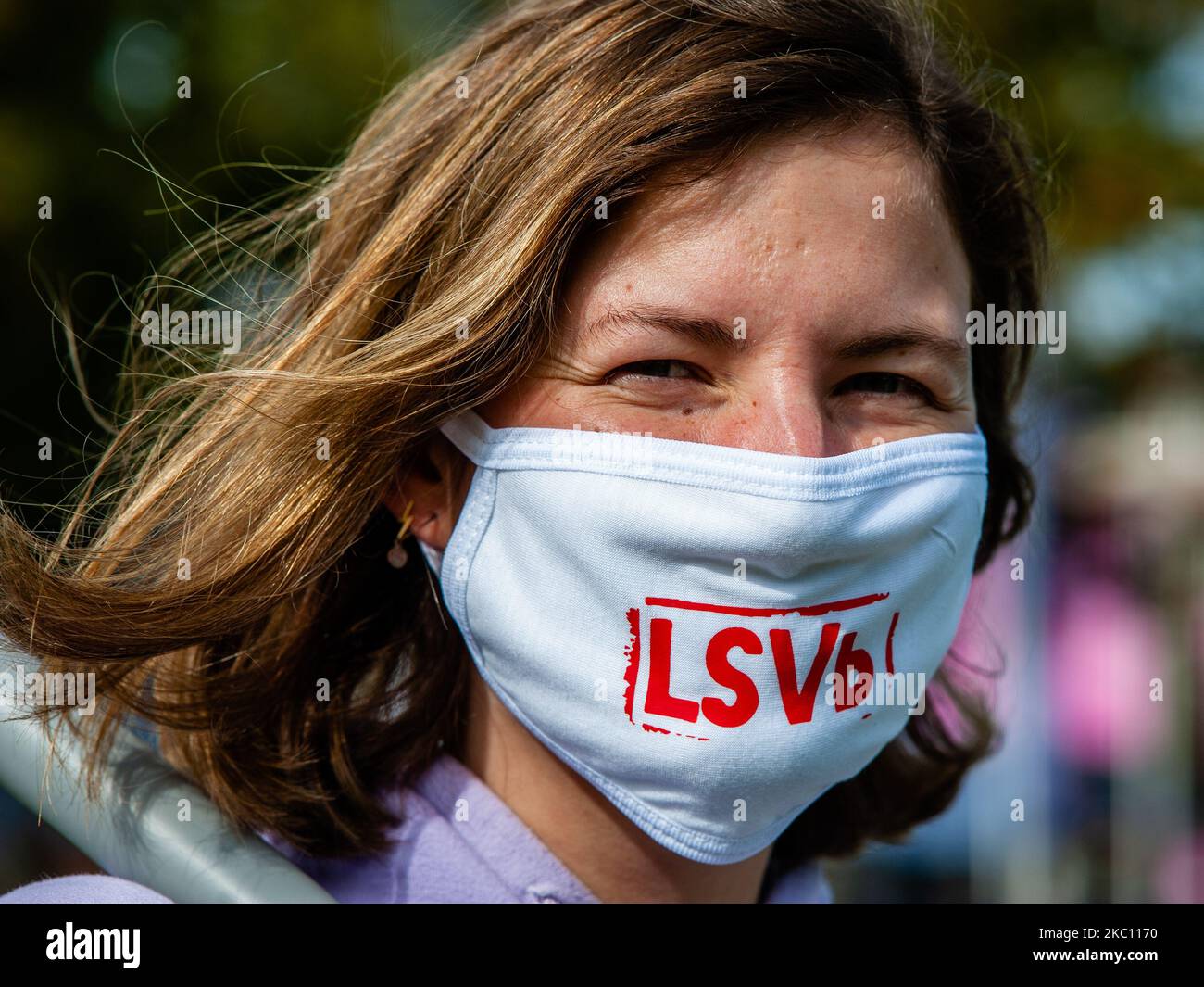A woman is wearing a mouth mask with the logo of one of the student ...