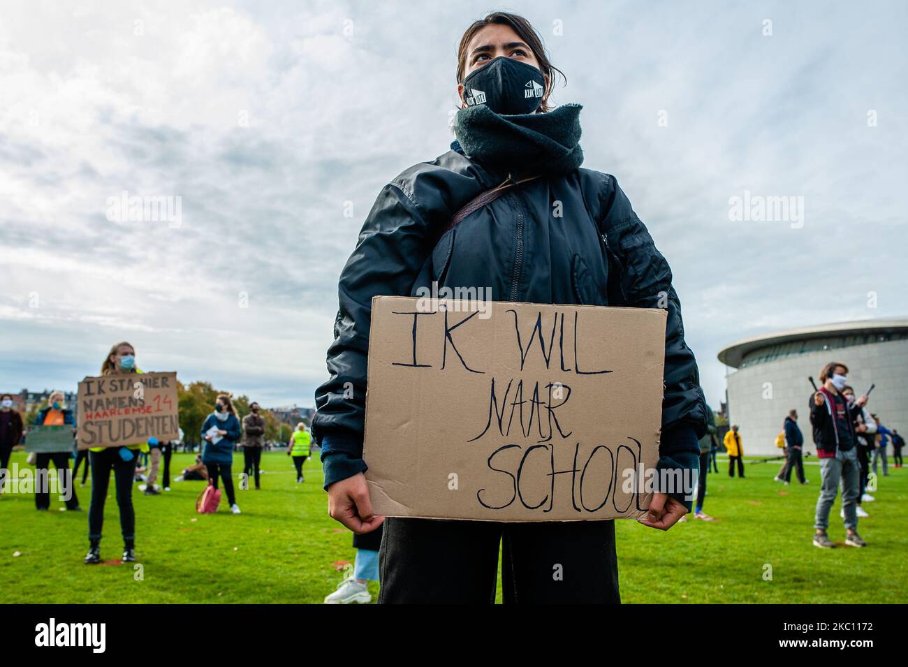 A woman is holding a placard that says I want back to school, during ...