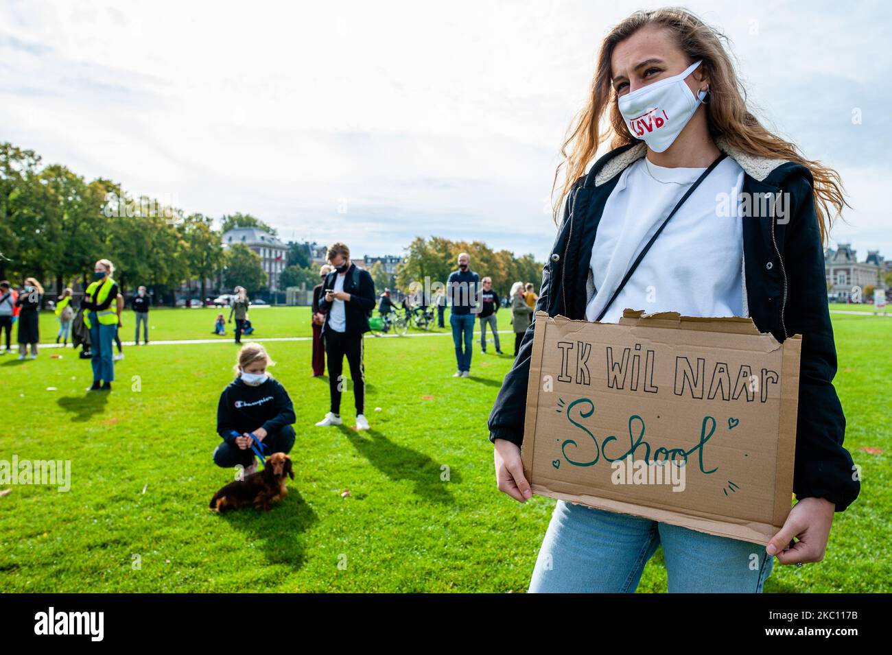 A woman is holding a placard that says I want back to school, during ...