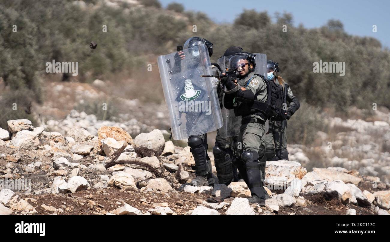 An Israeli soldier points his weapons at Palestinian protesters during ...