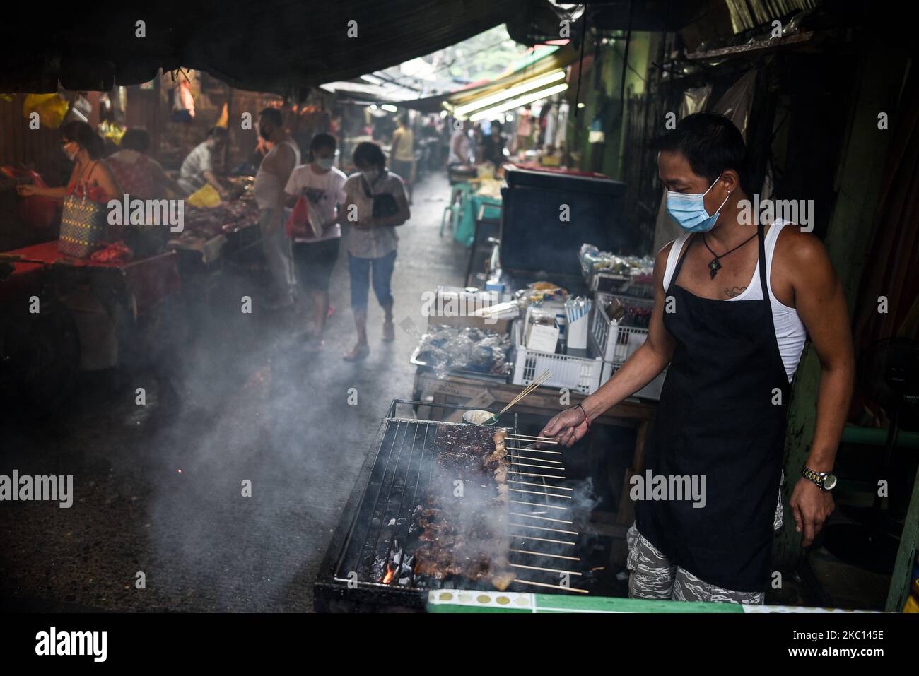 A man wearing a face mask prepares pork barbeque at a public market in ...