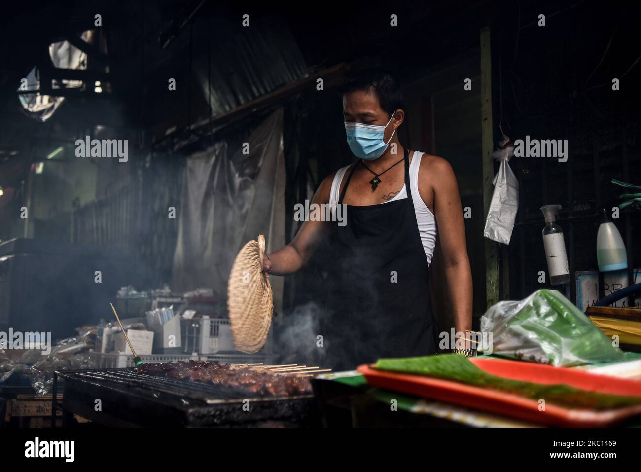 A man wearing a face mask prepares pork barbeque at a public market in ...