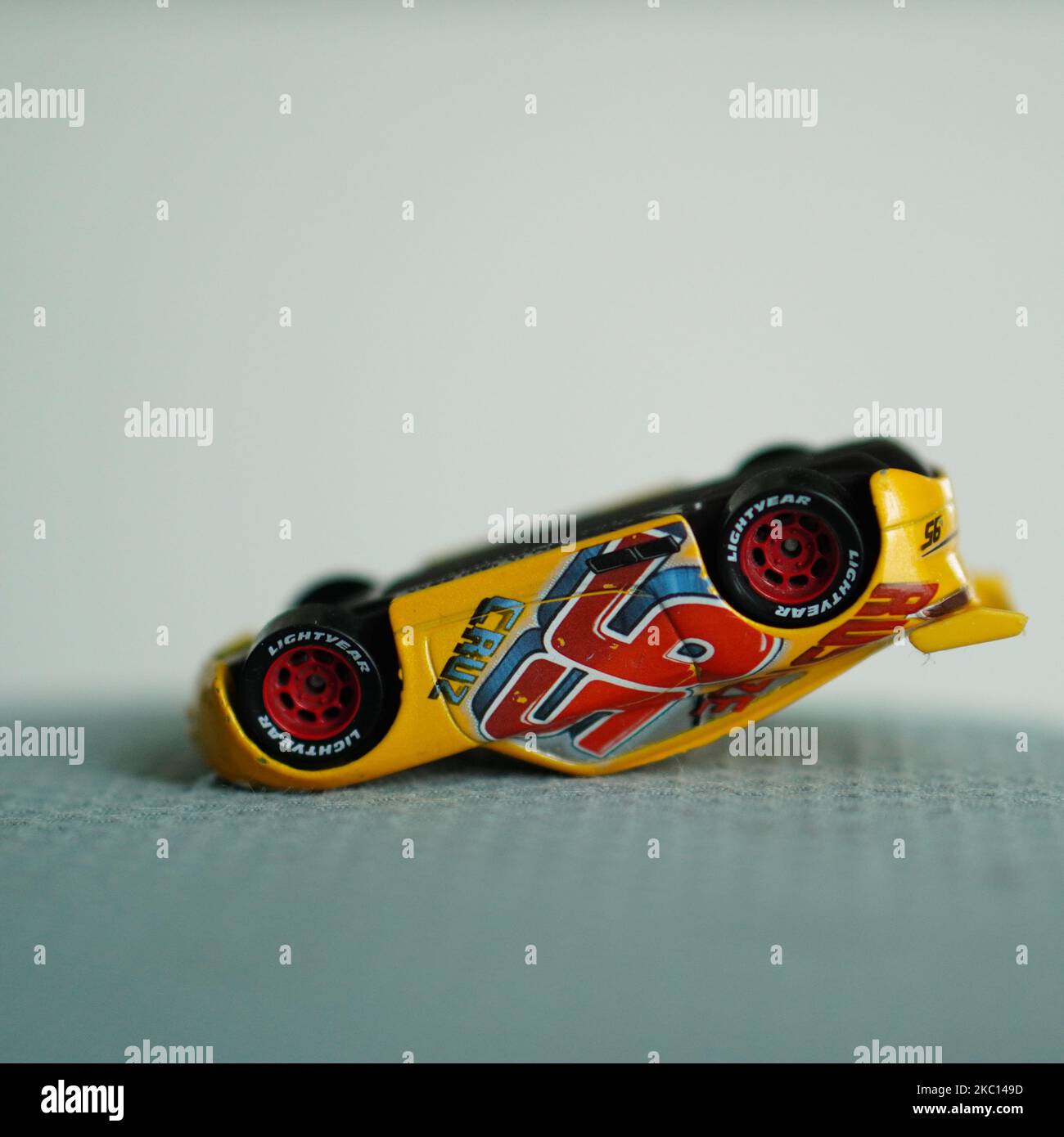 A yellow Cruz Ramirez toy model sport car laying upside downof the ...