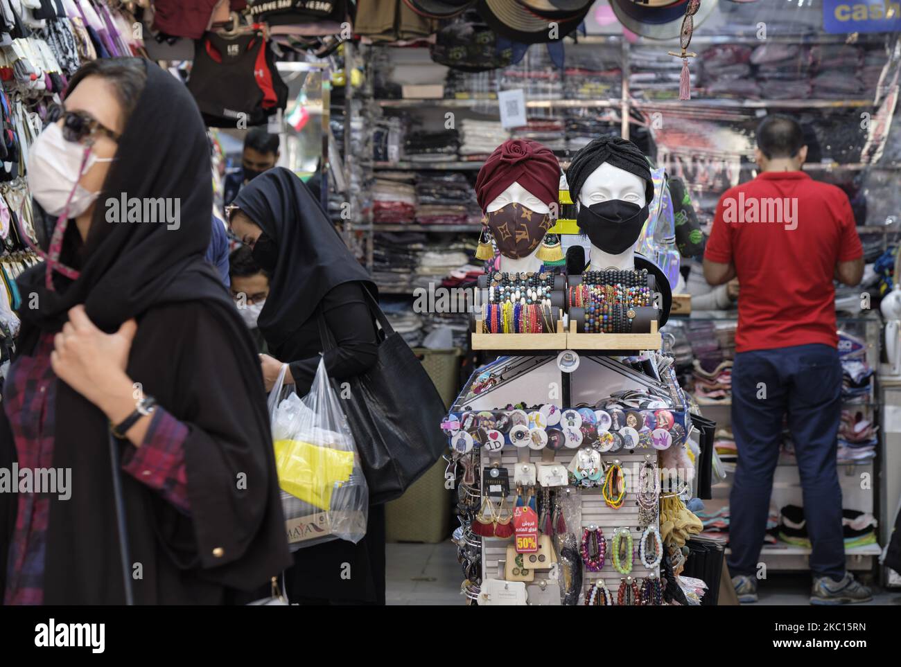 Iranians wearing face masks purchase as two mannequins are covered with ...