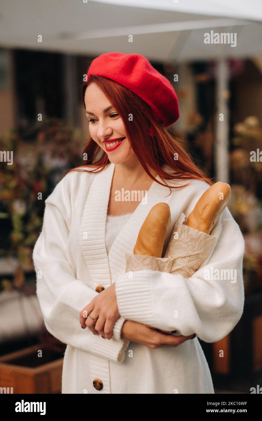 Portrait of a pretty woman in a red beret and a white cardigan with ...