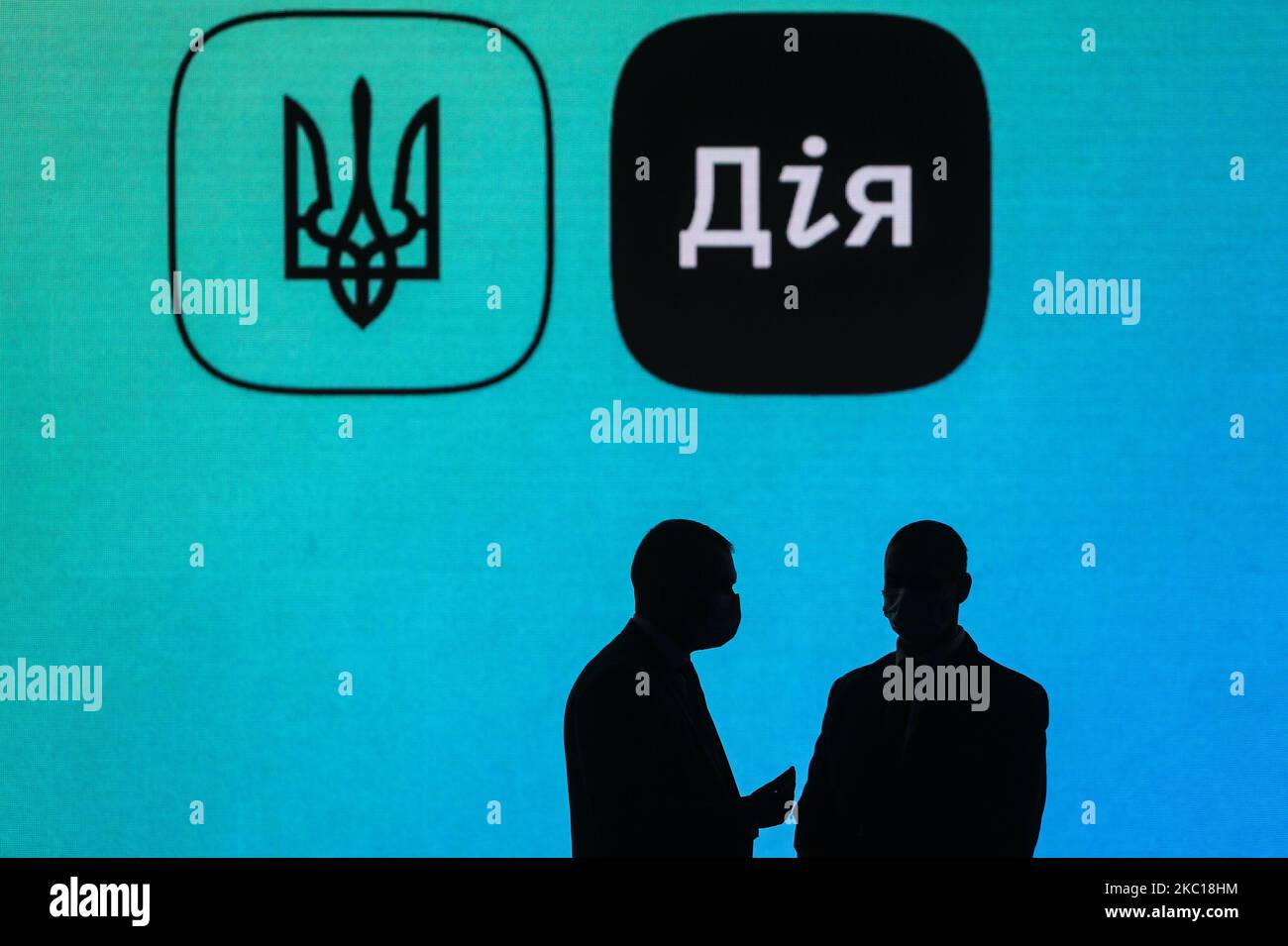 Silhouettes of people standing in front of the screen with a logo of ...