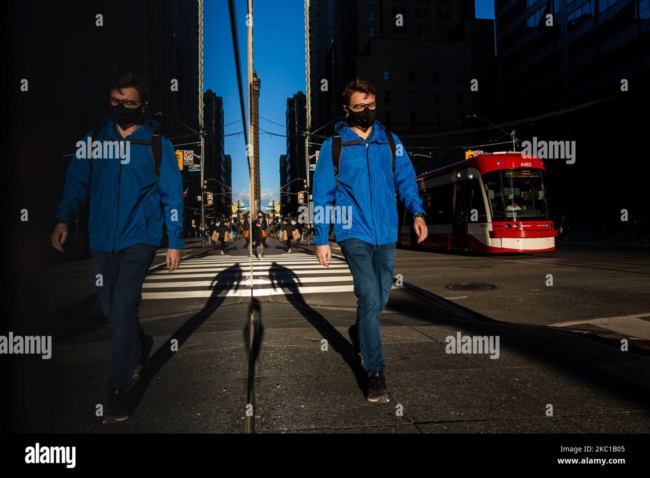 A person is reflected as they walk through Toronto's financial district ...