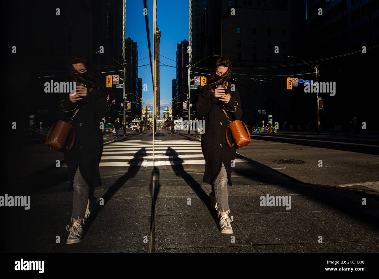 A person is reflected as they walk through Toronto's financial district ...