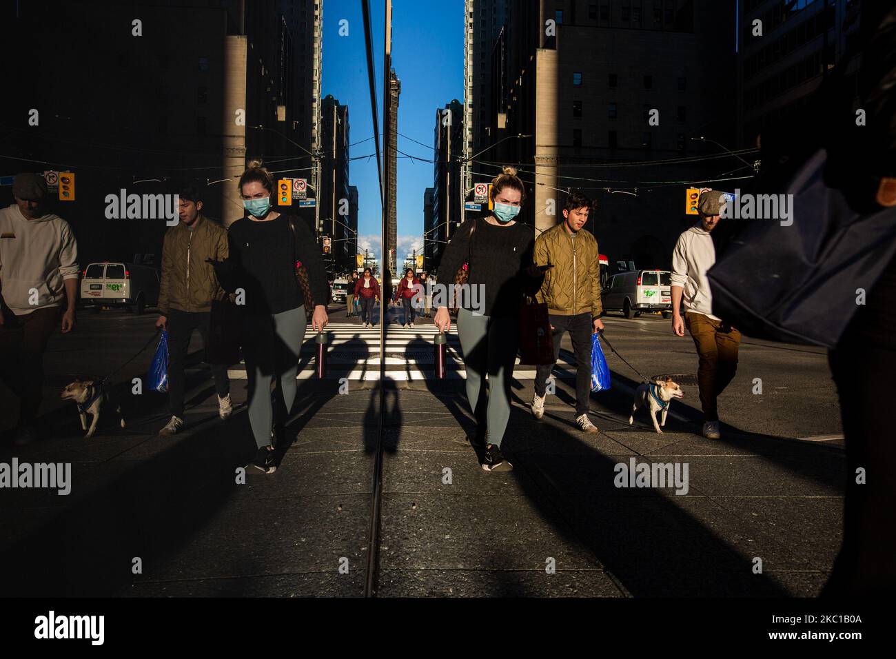 People are reflected as they walk through Toronto's financial district ...
