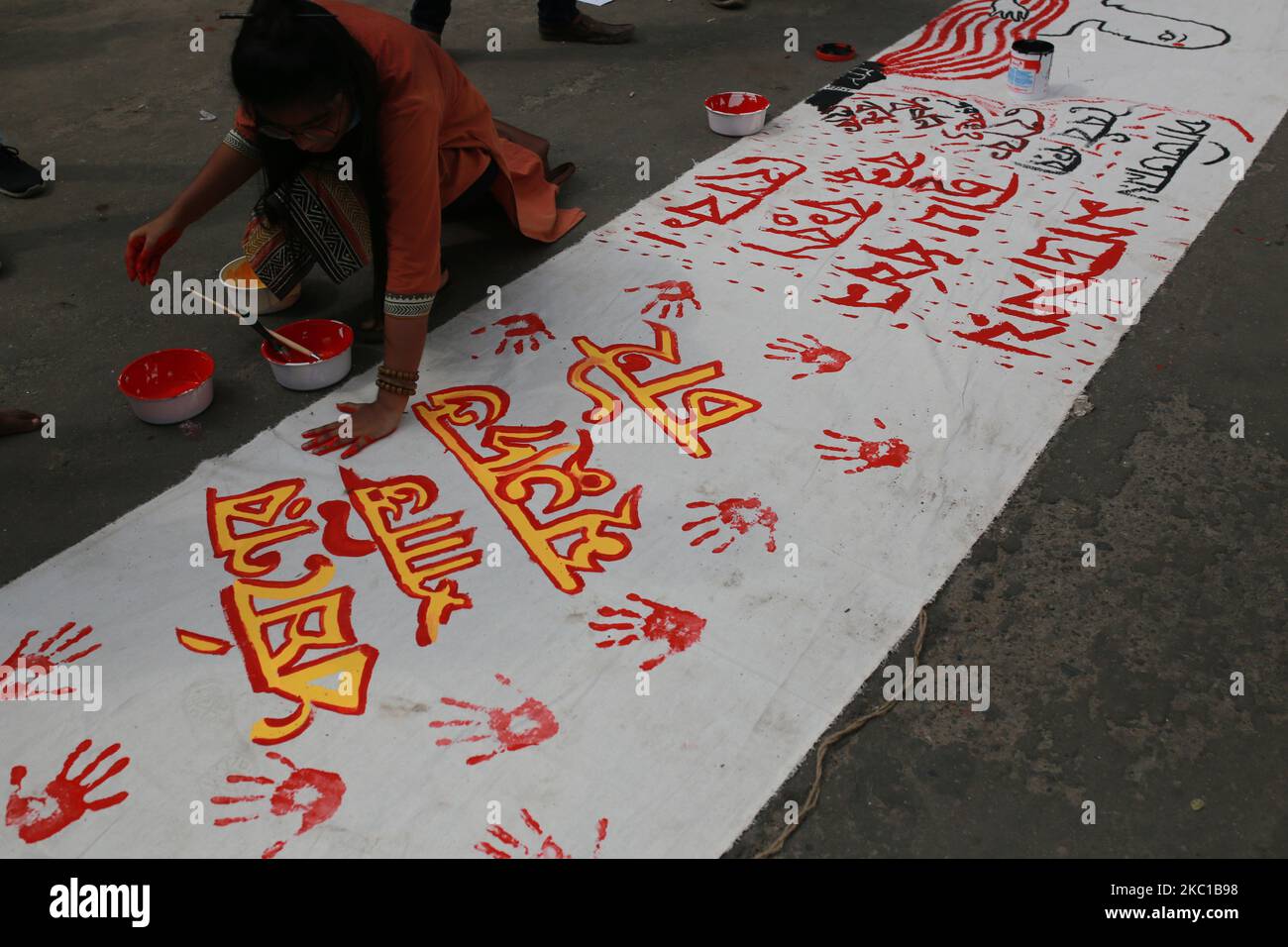 A student paints on a banner as part of protest against an alleged gang ...