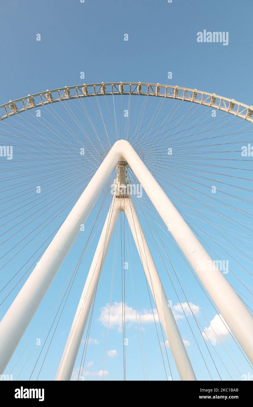 White Ferris wheel with glass light blue cabins against blue sky, Dubai ...