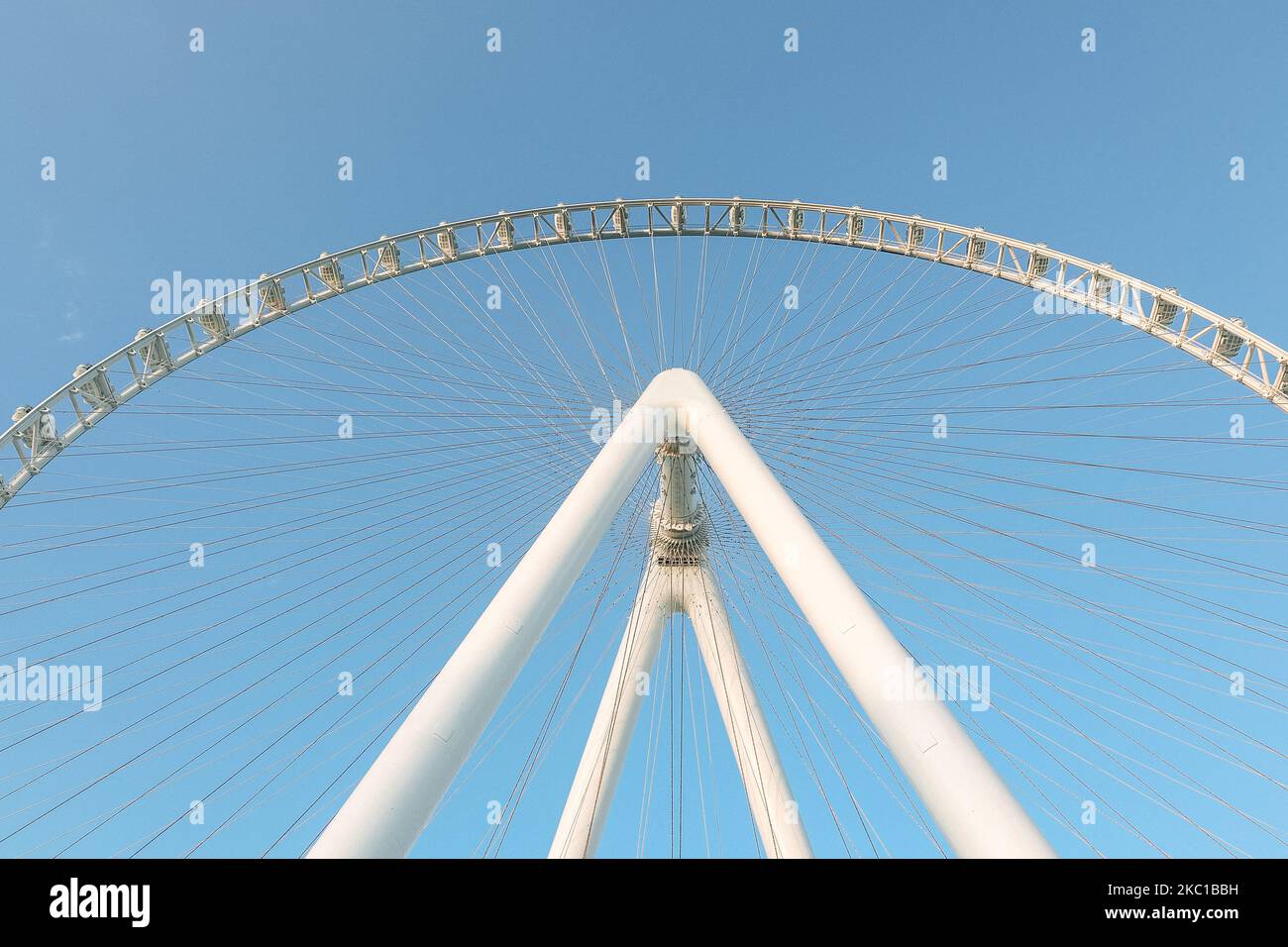 White Ferris wheel with glass light blue cabins against blue sky, Dubai ...