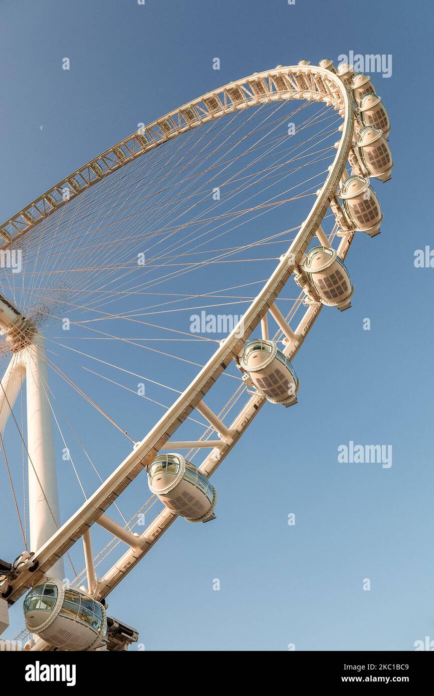 White Ferris wheel with glass light blue cabins against blue sky, Dubai ...