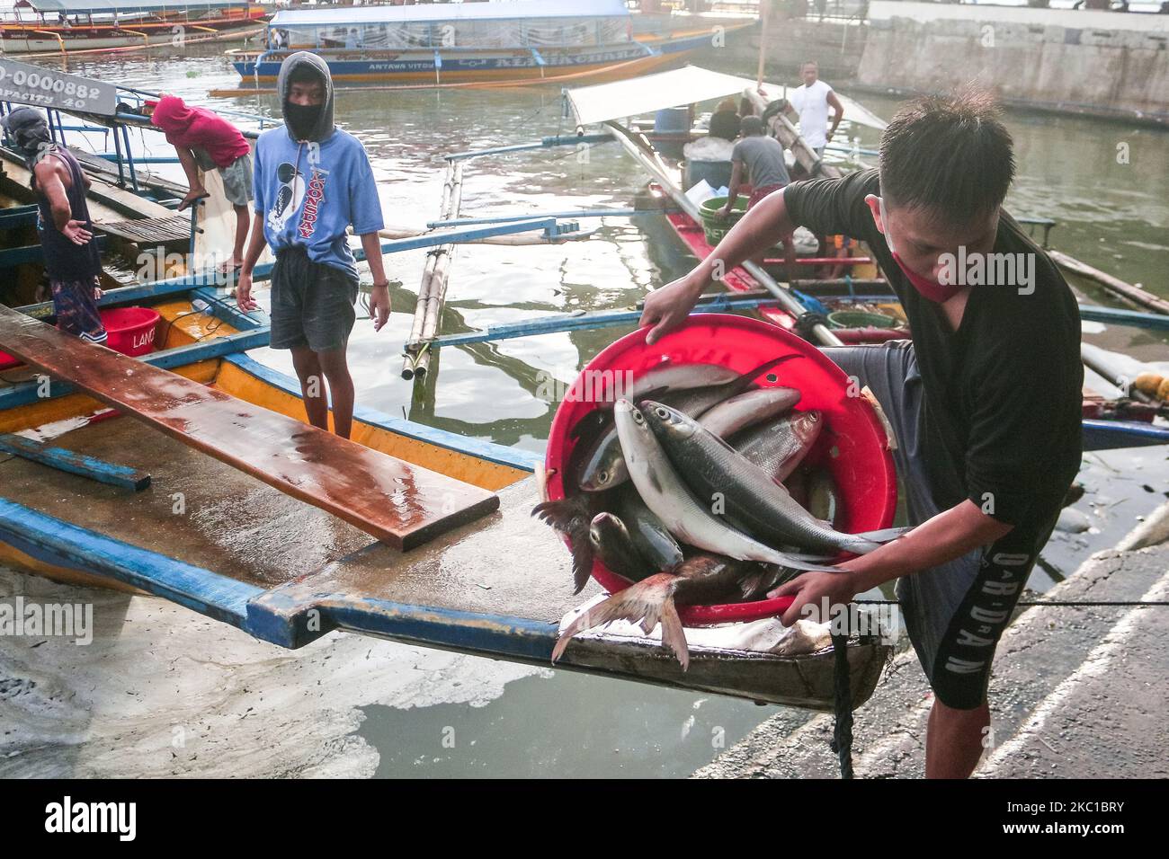 A group of fish porter in Binangonan, Rizal are unloading the basin ...
