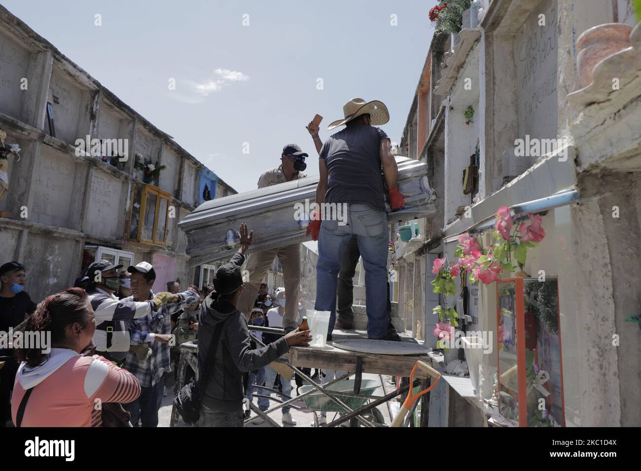 Gravediggers enter a coffin with the body of a deceased person in a ...