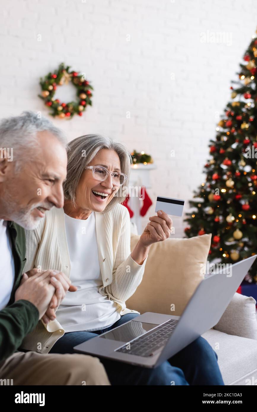 happy mature man near wife with credit card looking at laptop while ...
