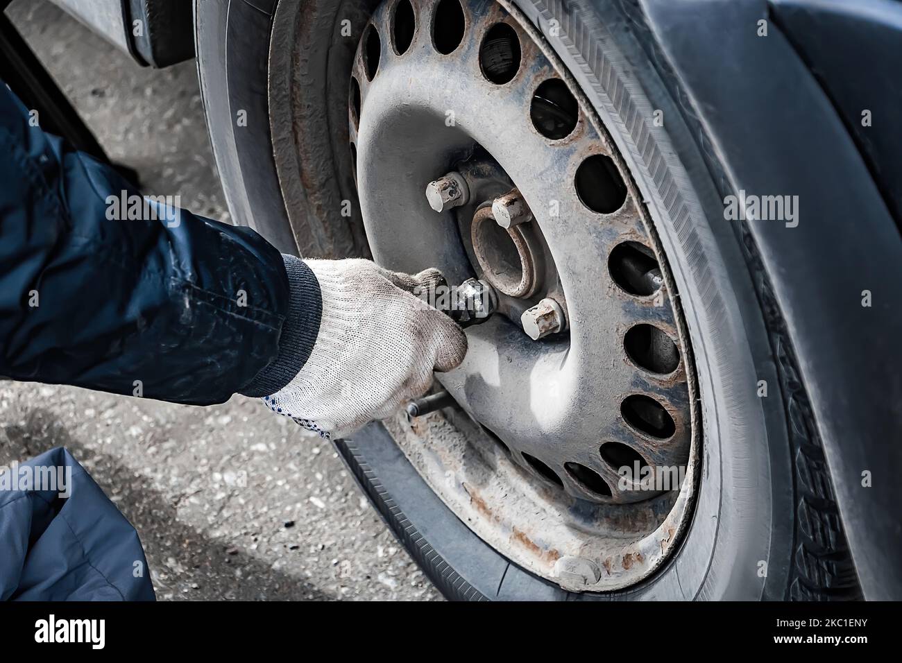 Auto mechanic changes wheel on old car. Man changes punctured tire ...