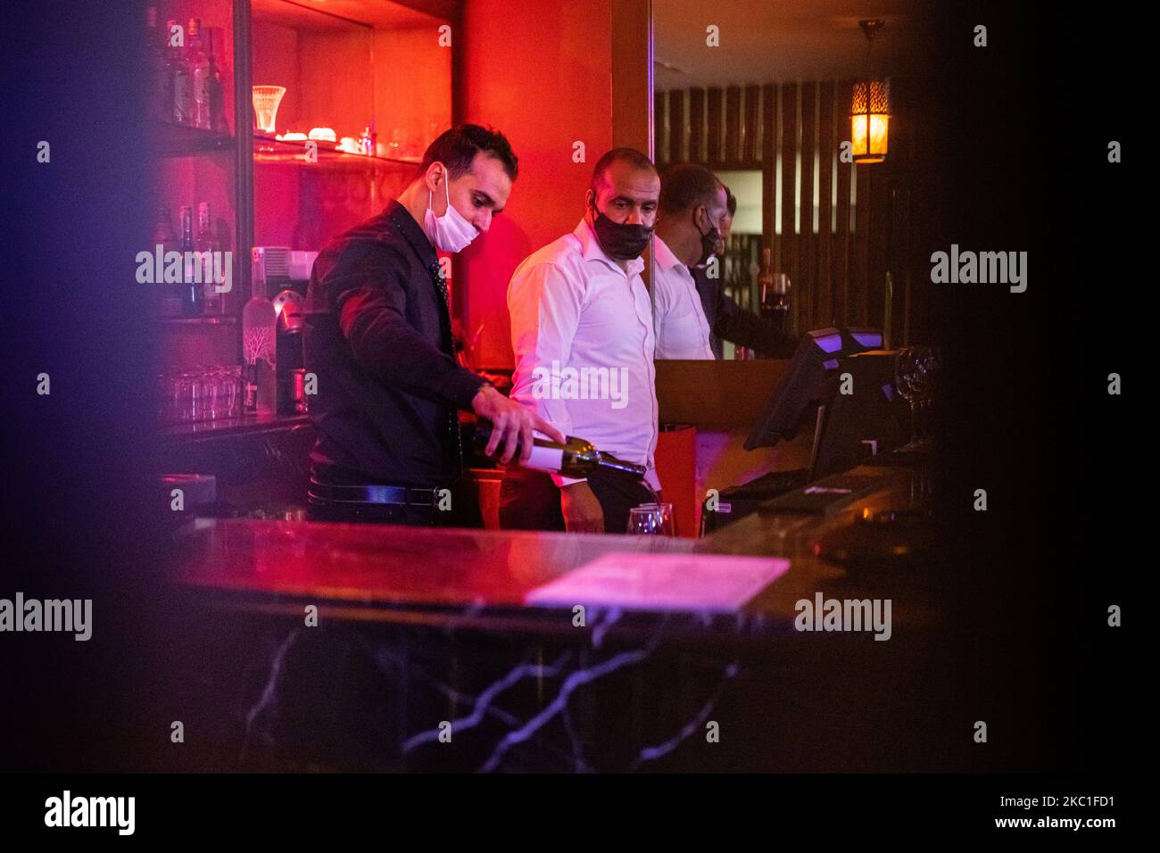 An Adult man wearing face mask pouring red wine into the wineglasses ...