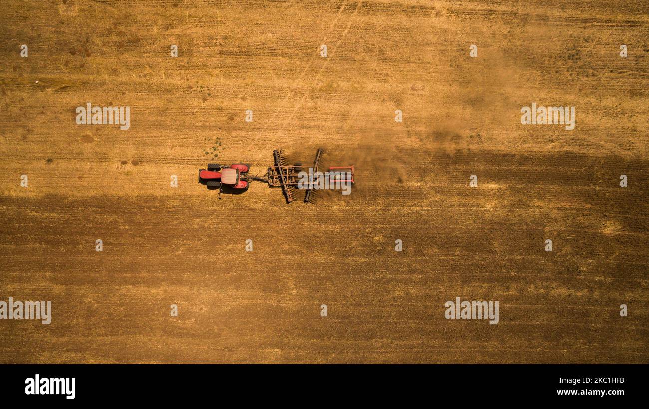 Aerial view of tractor cultivating and harrowing field at spring season ...