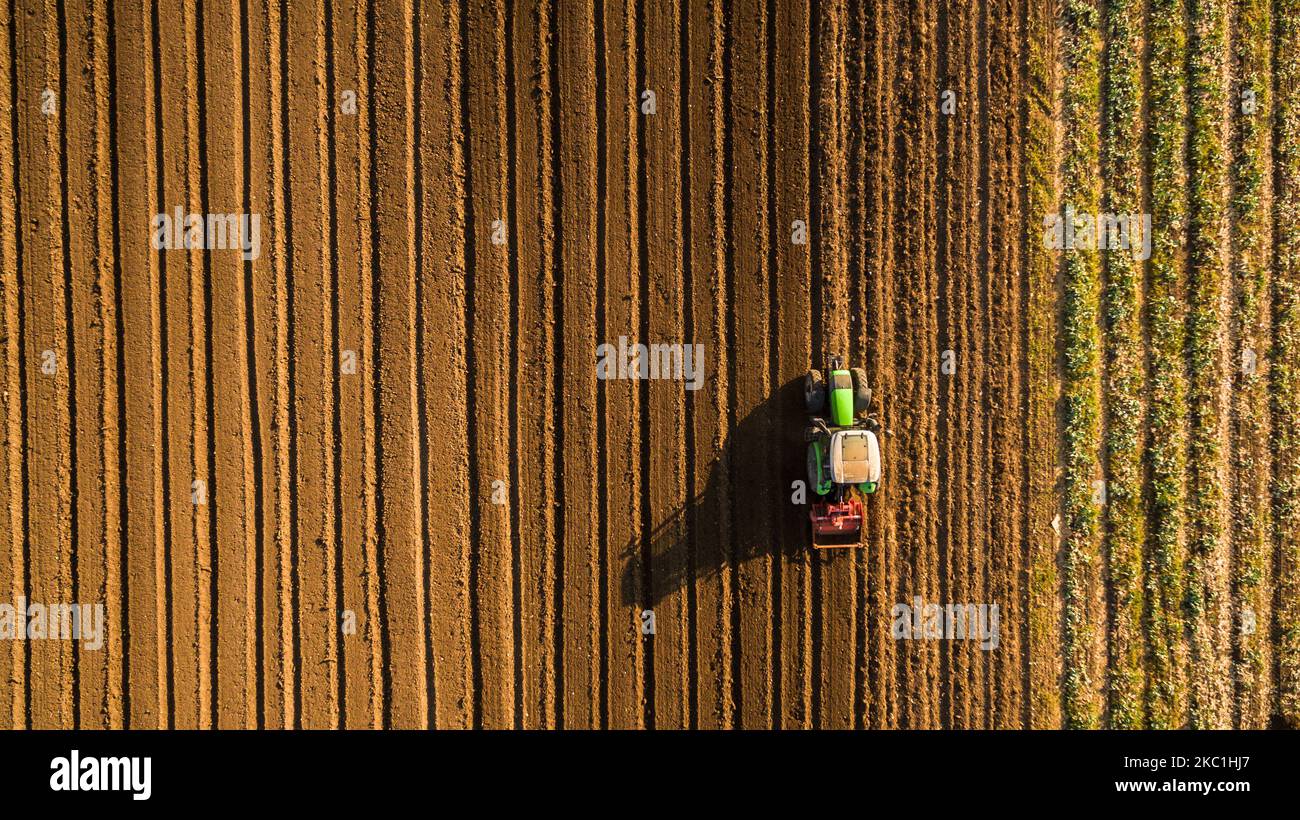 Aerial view of tractor cultivating and harrowing field at spring season ...