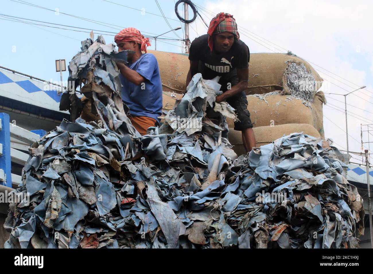 Indian worker carrying tanned animal hides to lode a truck at a tannery ...