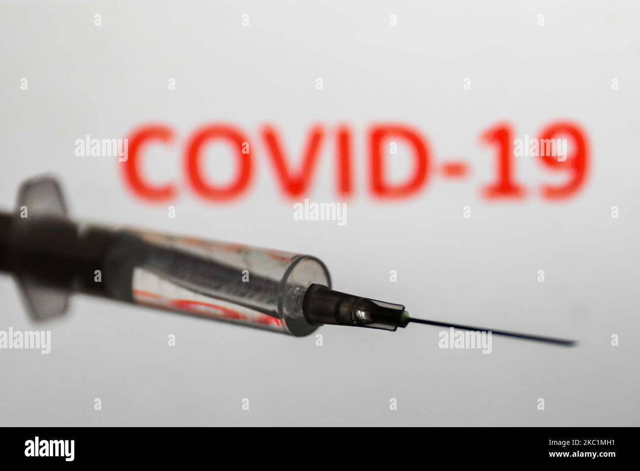 Medical syringe is seen with 'covid-19' sign displayed on a screen in ...