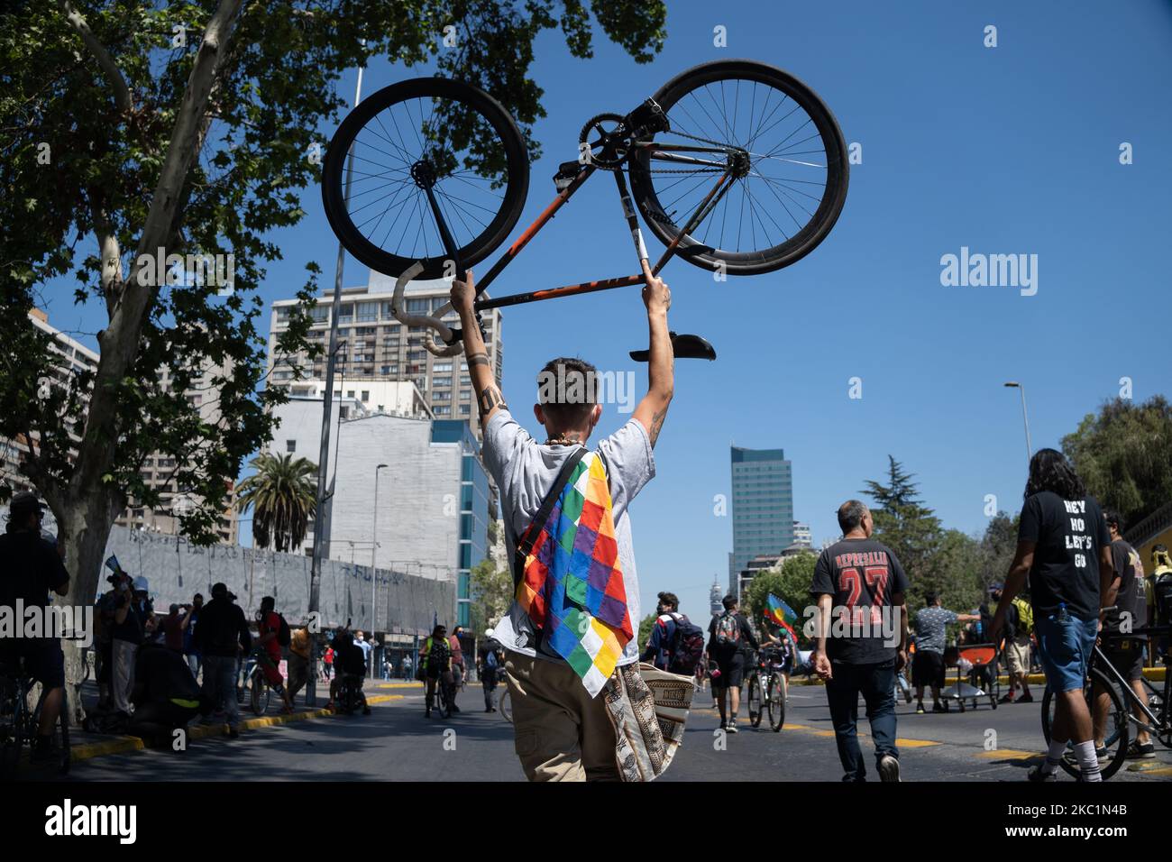 A man lifts his bicycle in protest. The flag of the indigenous peoples ...