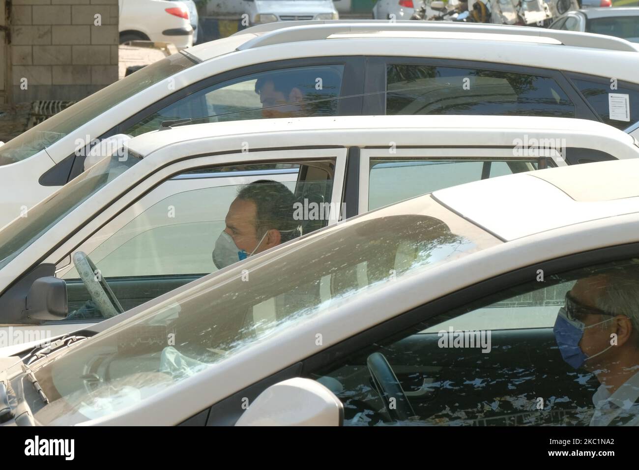 Iranian drivers wearing protective face masks sit in their vehicles ...