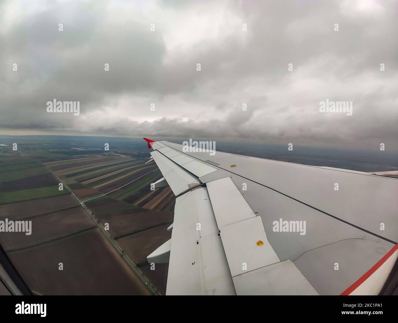 Wing view from the window of the plane with clouds and Austrian fields ...