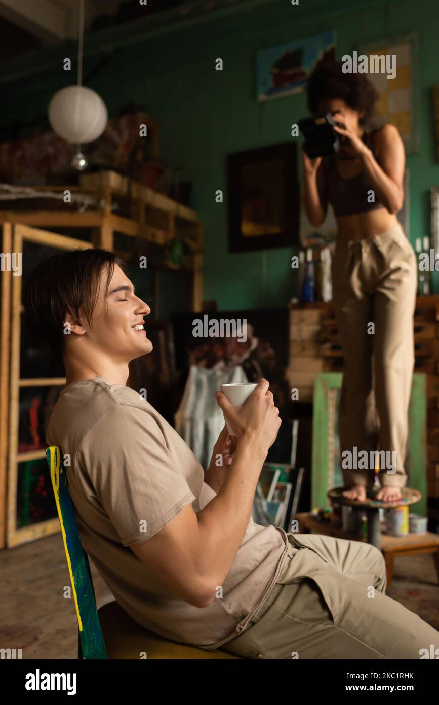 blurred african american woman standing on chair and taking photo of ...