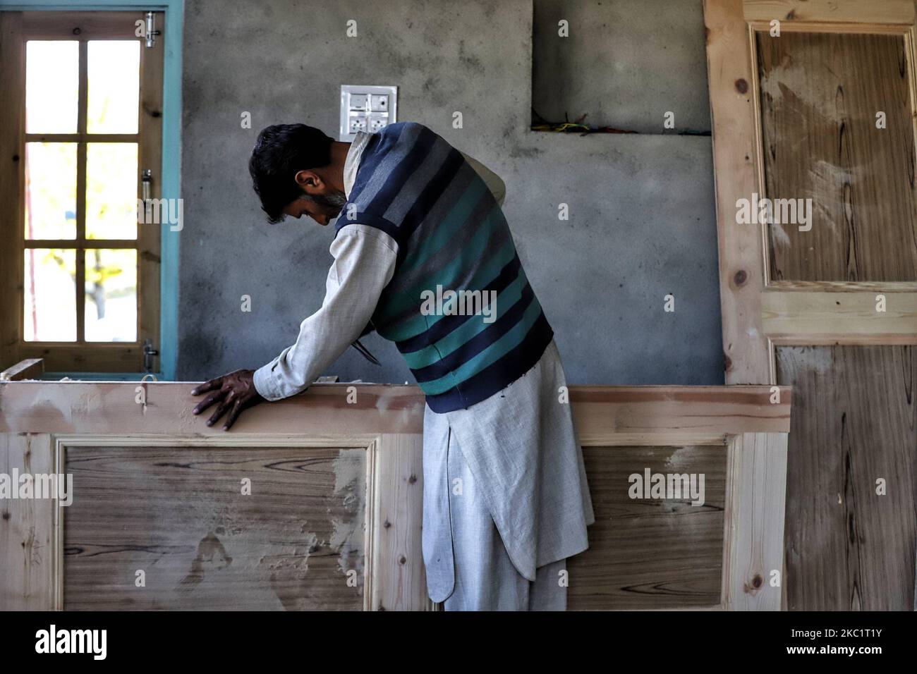 A carpenter works at a site on the outskirts of Sopore Town, District ...