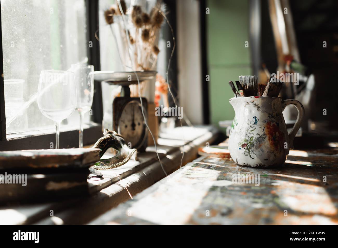 handmade jug with paintbrushes near vintage scales and glasses on ...
