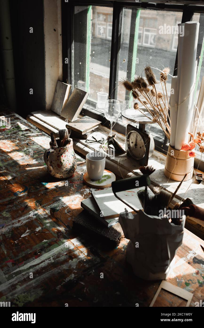 stucco vase and jug with art tools near books and vintage scales on ...