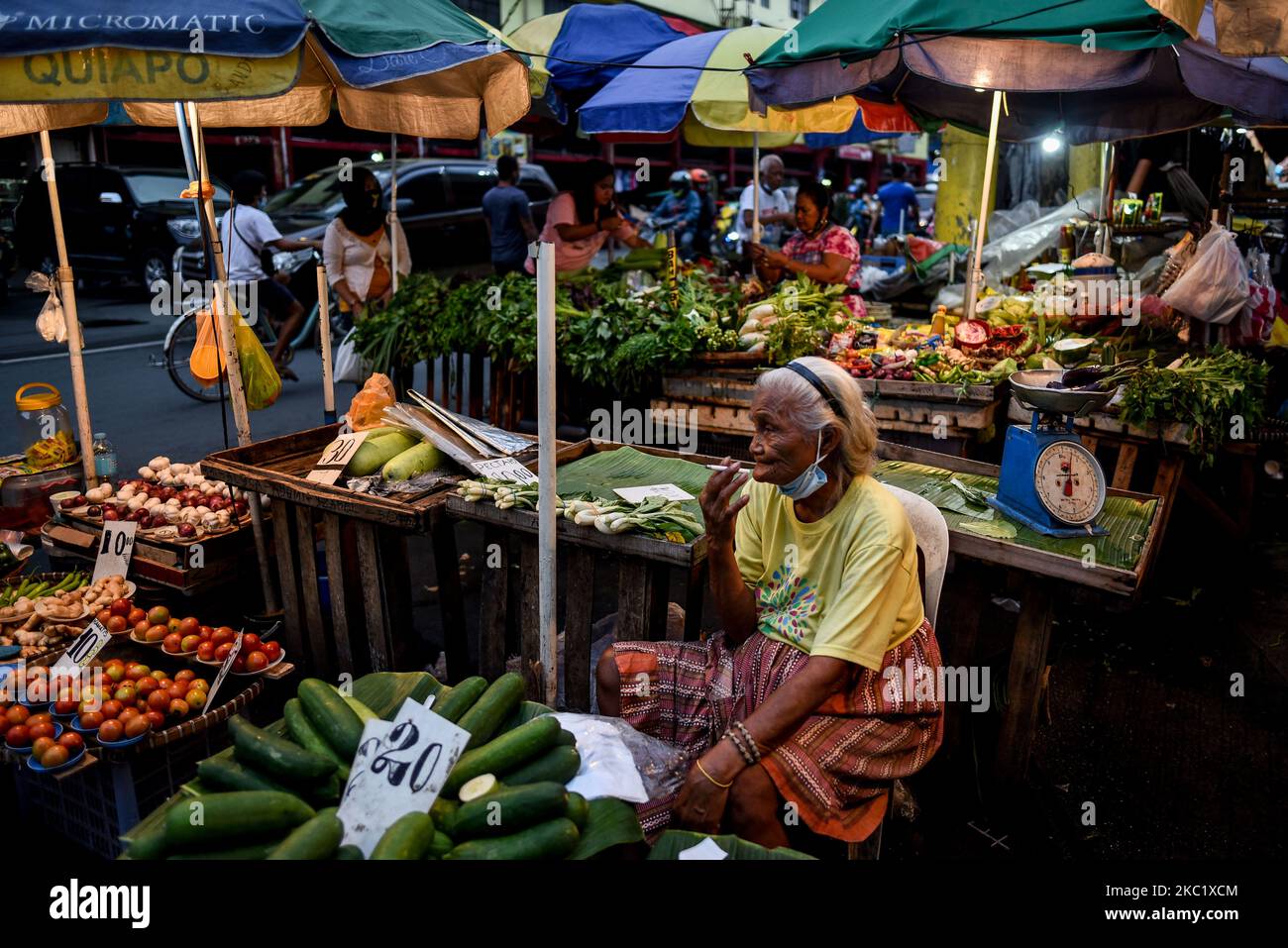 A vendor smokes a cigarette at her stall at a market in Manila ...