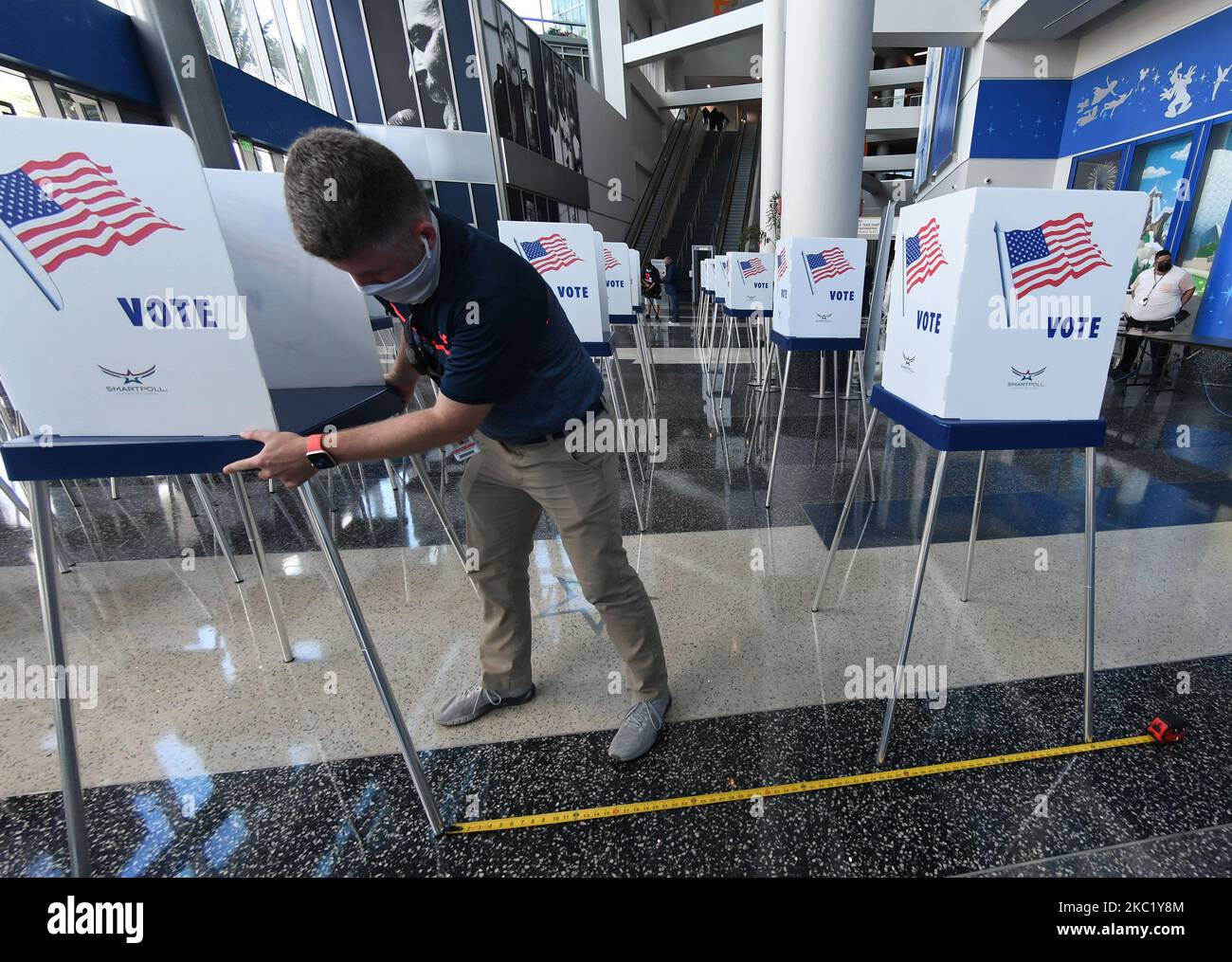 Workers set up voting booths six feet apart for social distancing at an ...