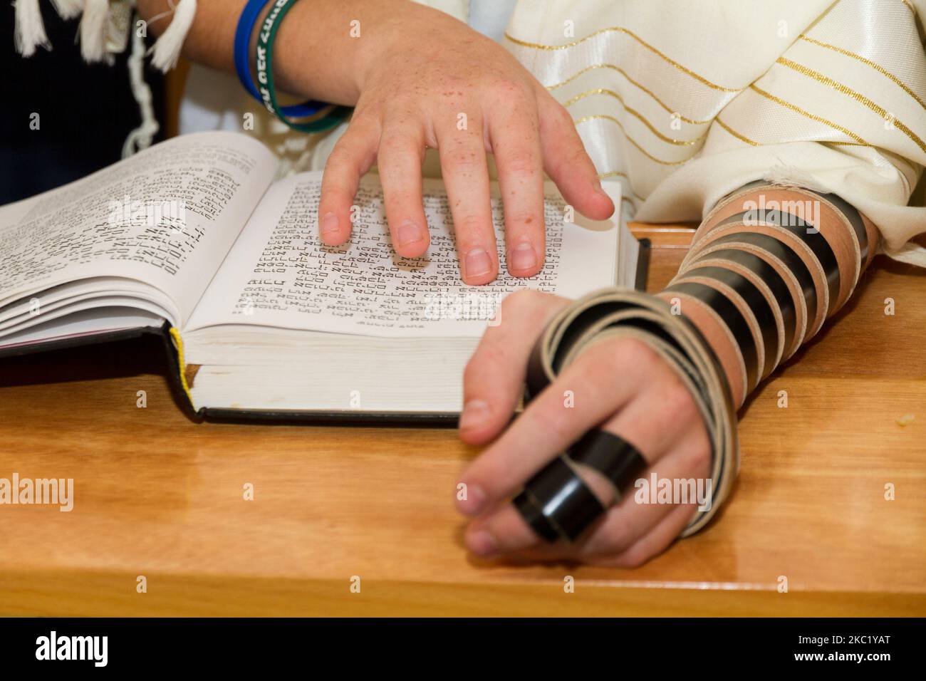 A young man pointing at a phrase in a bible book (sefer torah), while ...