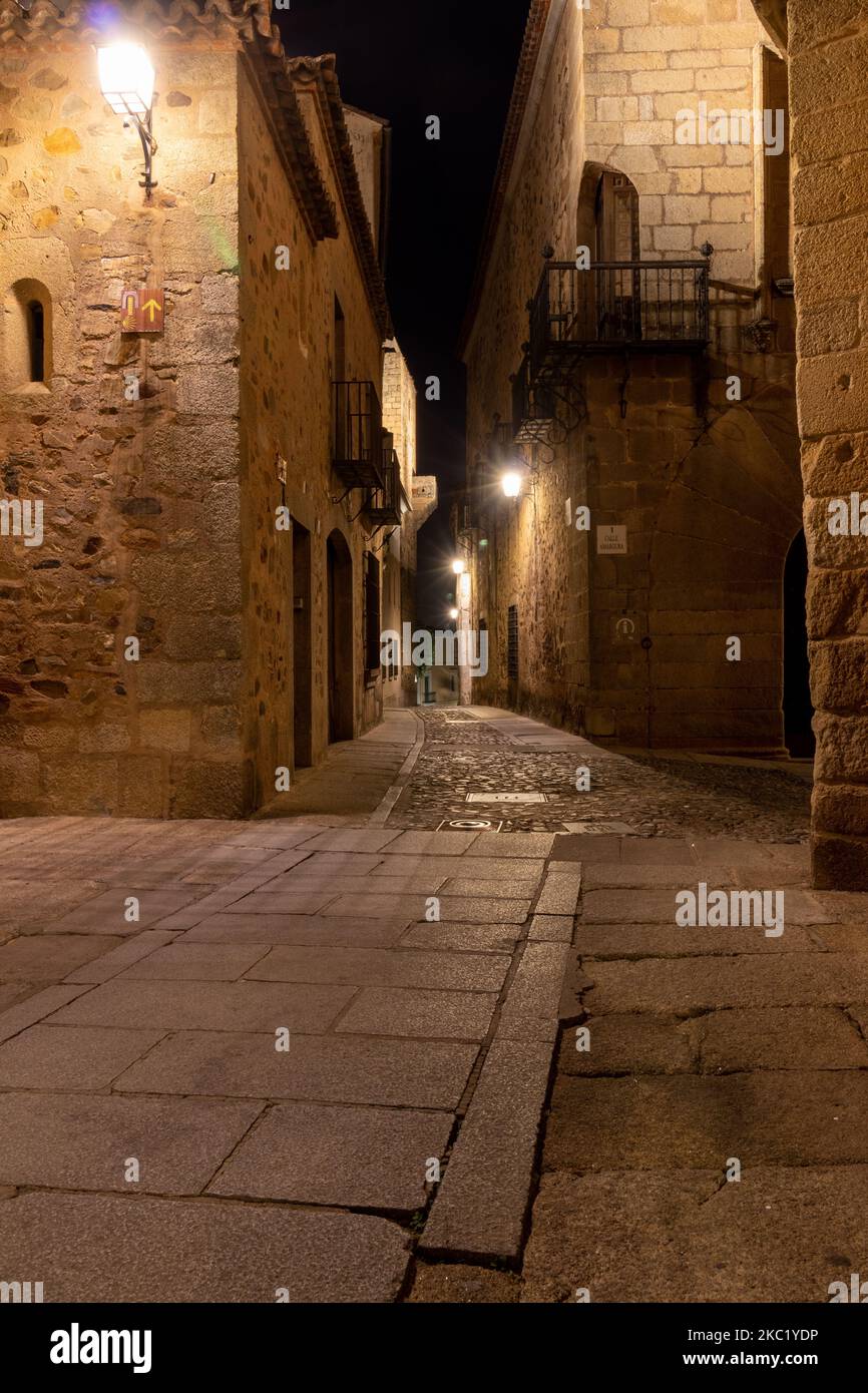The illuminated old empty alley with concrete buildings at night in Old ...