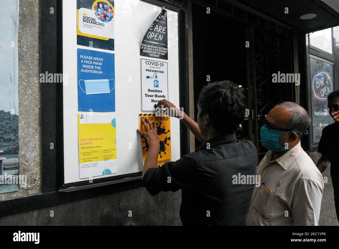 Cinema hall staff hanging information on a notice board outside a movie ...