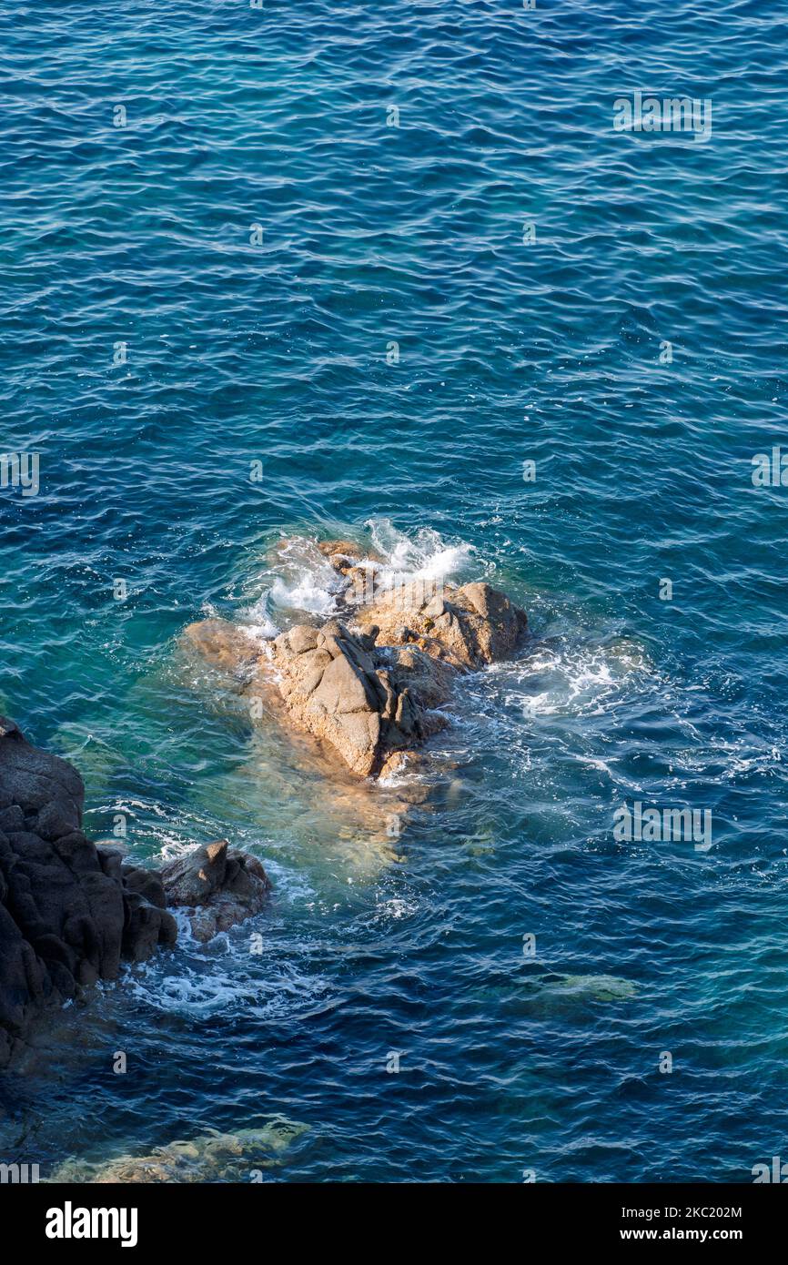 Wild rocky beach coastline and the sea, wave splashes on rock in sea ...