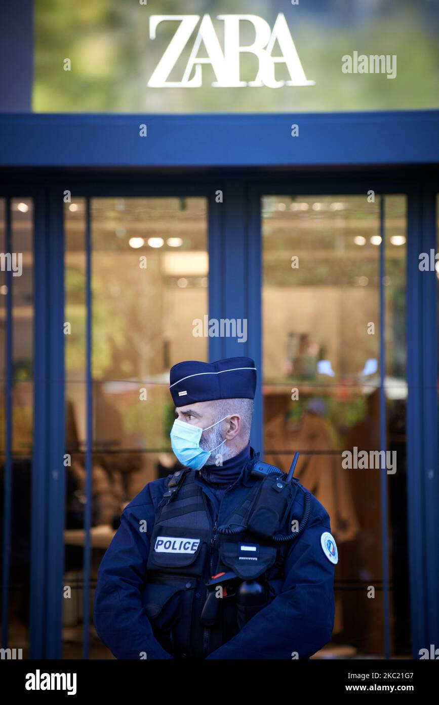 A policeman stands guard in front of the Zara shop. Members and ...