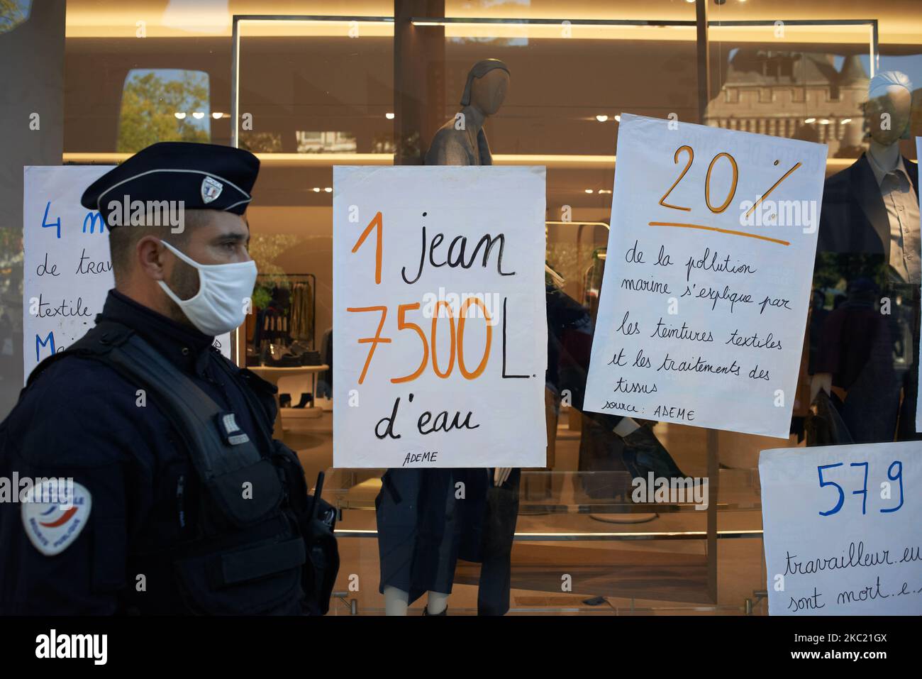 A police man walks in front of placards glued ont the Zara shop windows ...